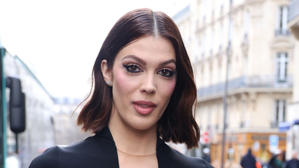 Iris Mittenaere prend la pose dans un polo à rayures, une jupe boule et un trench beige pour se ...